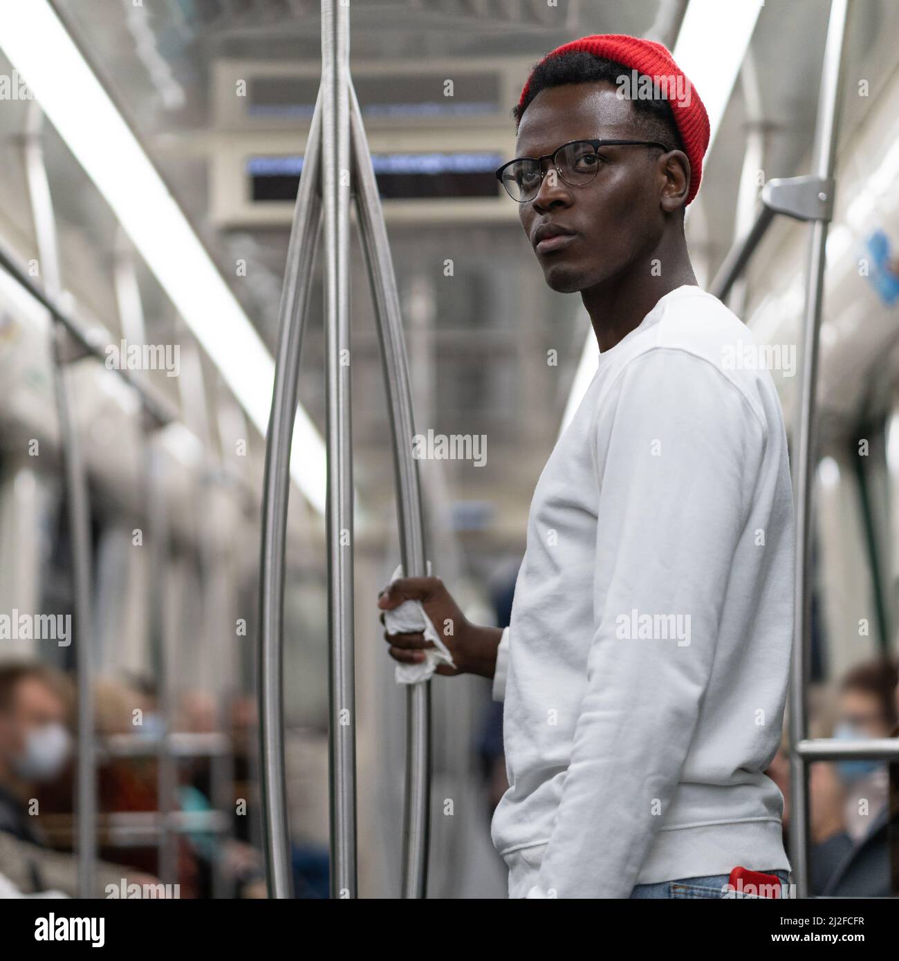 Portrait of thoughtful Black student man in red hat holding handrail ...