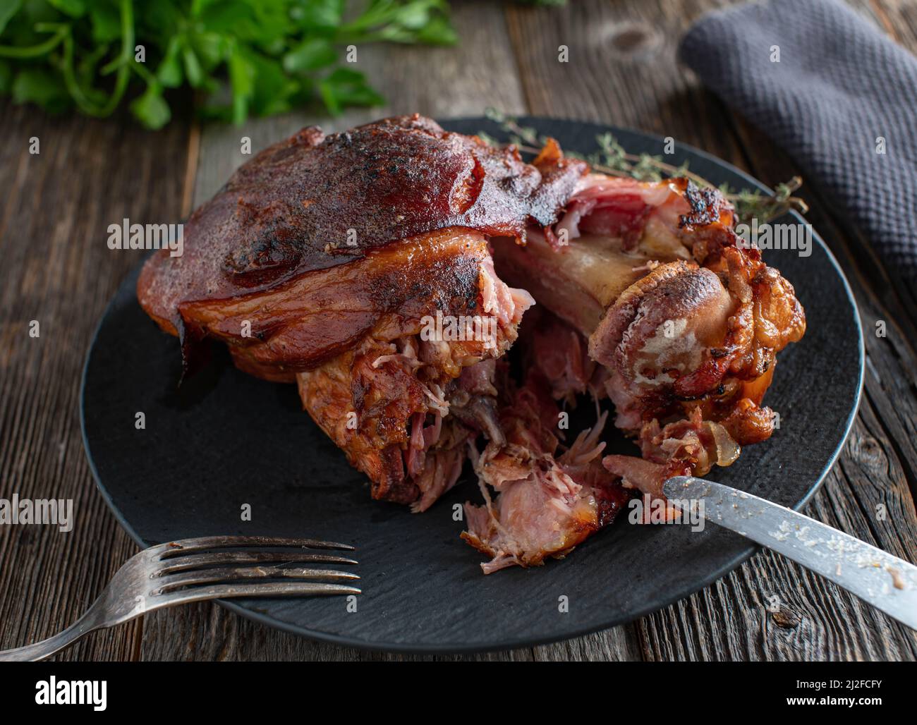 Grilled pork knuckle or ham hock on a black plate on dark wooden table ...