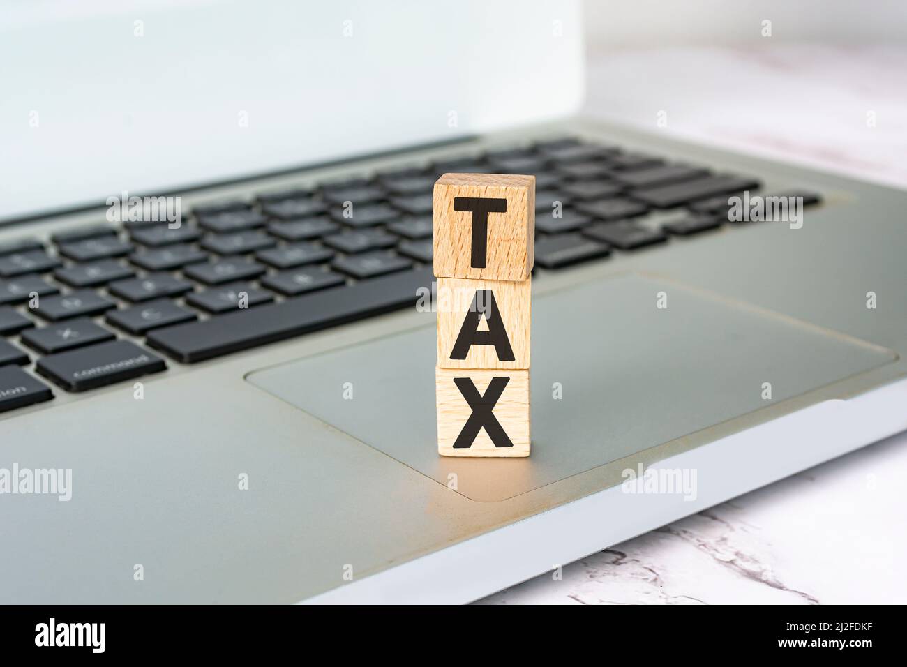 Tax text on wooden block cube placed on laptop or notebook. Tax time ...