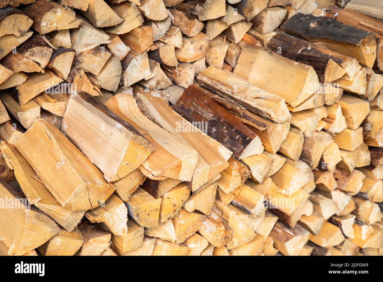 Stock of firewood, a lot of birch chocks lay stacked in rural barn ...