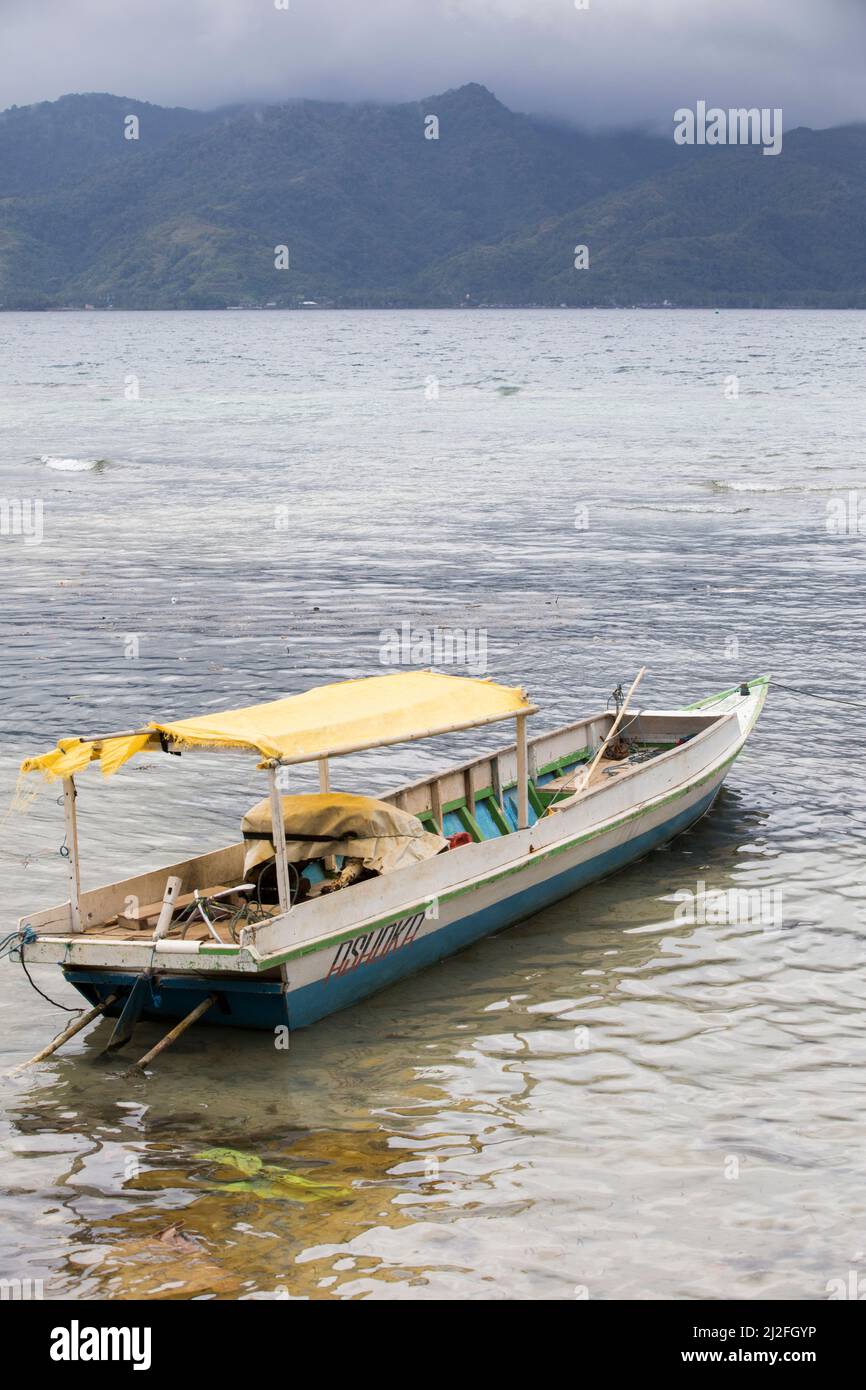 A passenger ferry boat is anchored on the coast of a small island off ...