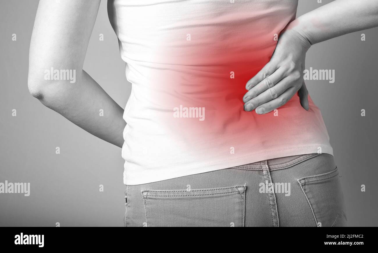 Backache. Woman holding painful lower back with red point closeup ...