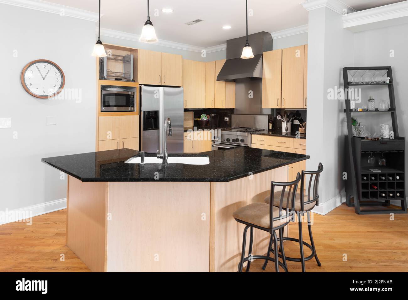 A luxury apartment condo with chairs sitting at a large island, black ...