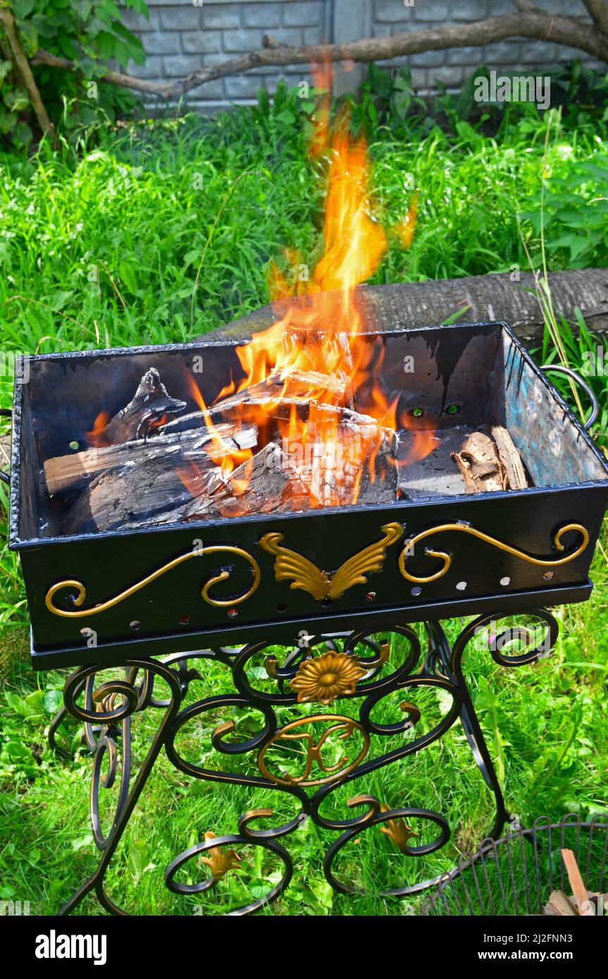 Lighting a fire in a metal grill for cooking kebabs and steaks ...