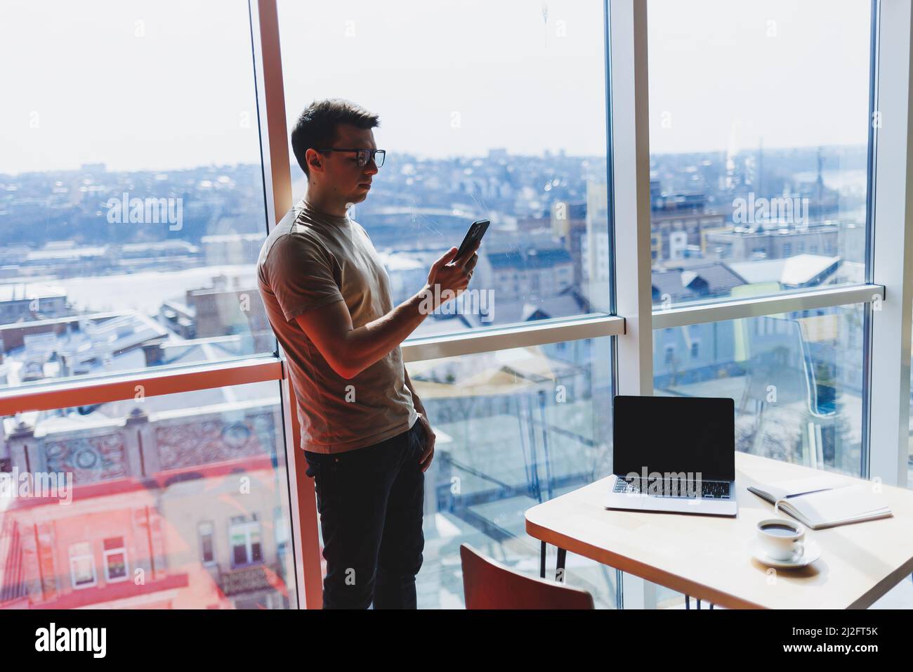 Cheerful scofe male entrepreneur standing near office window and ...