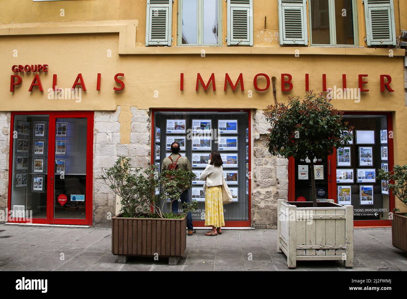 A couple looks at properties for sale in Groupe Palais Immobilier, a real estate agency Stock ...