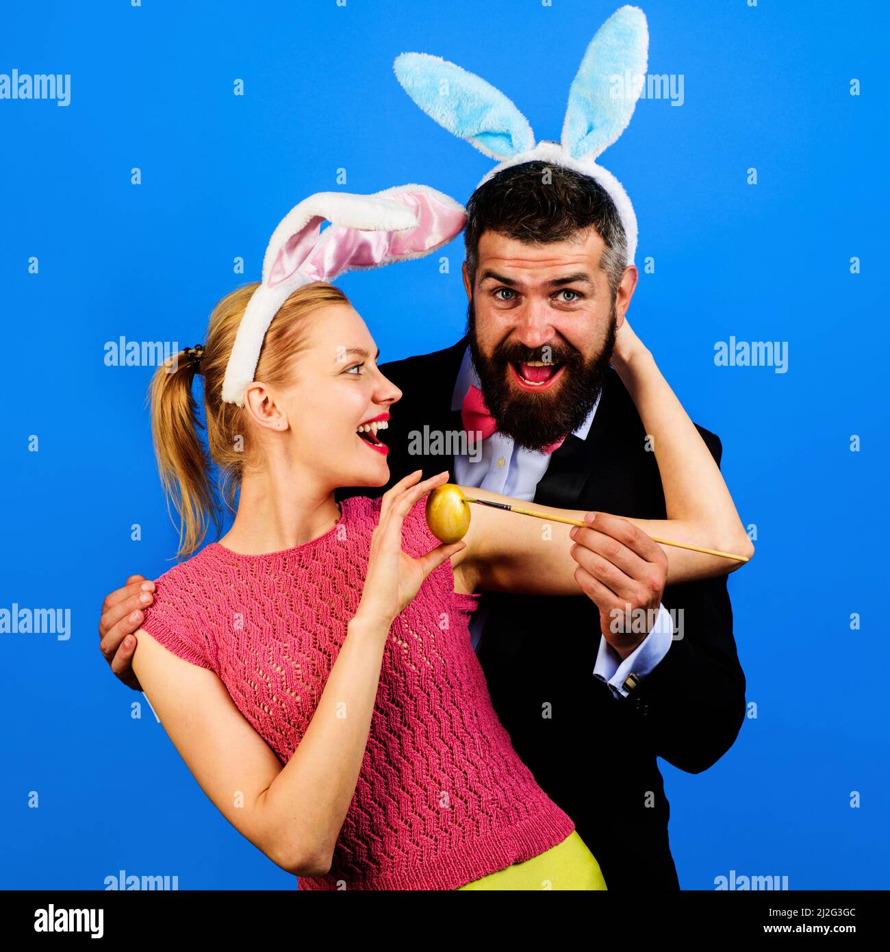 Family celebrating Easter. Bunny couple in rabbit ears painting egg for ...