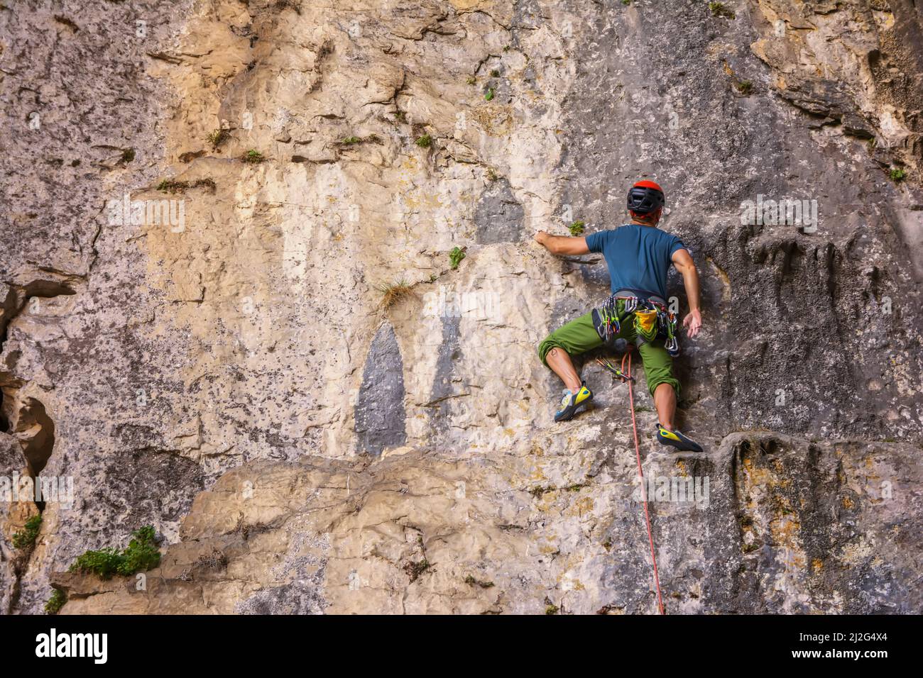 Young man climbs on a rocky wall in a cave. Man climbing on a big ...