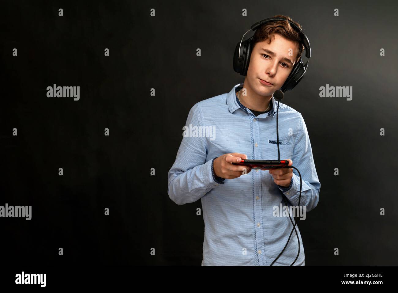 A teenage boy in headphones playing a game on his smartphone. Black ...