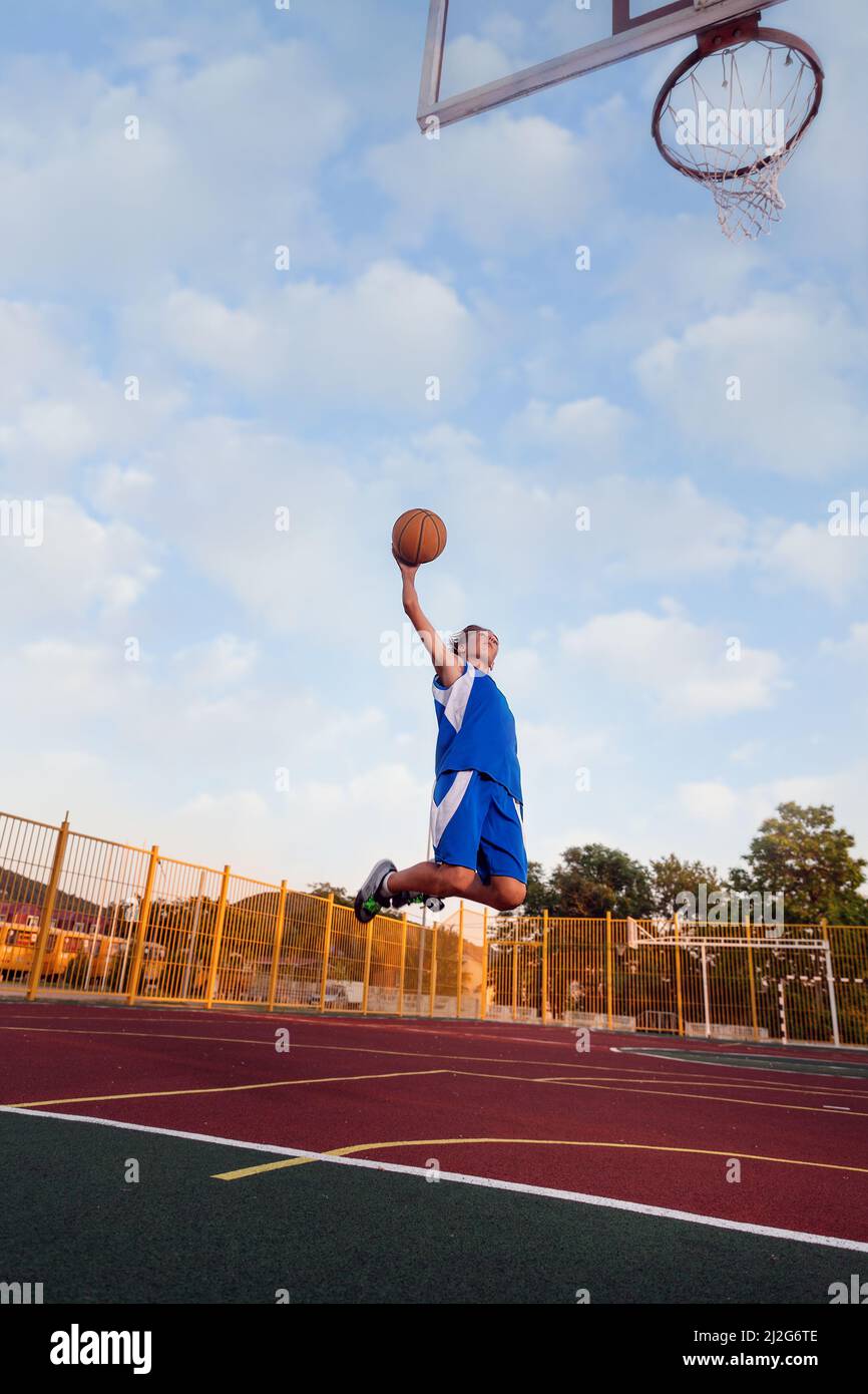 Basketball. A Teenage boy in blue sportswear jumps and throws a ball ...