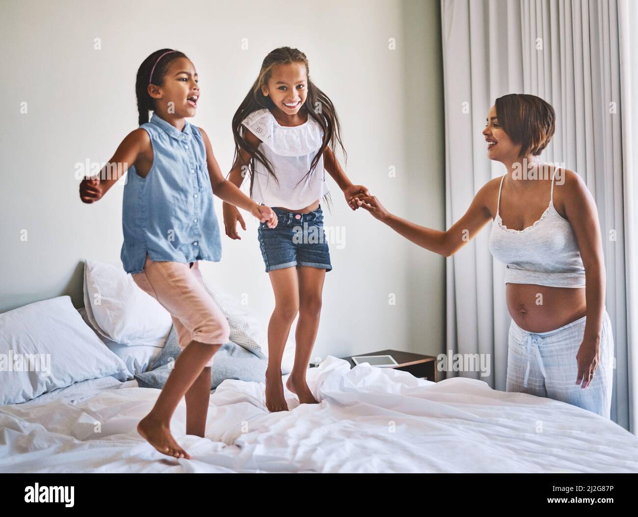 Jumping around. Shot of a cheerful young family jumping around on a bed ...