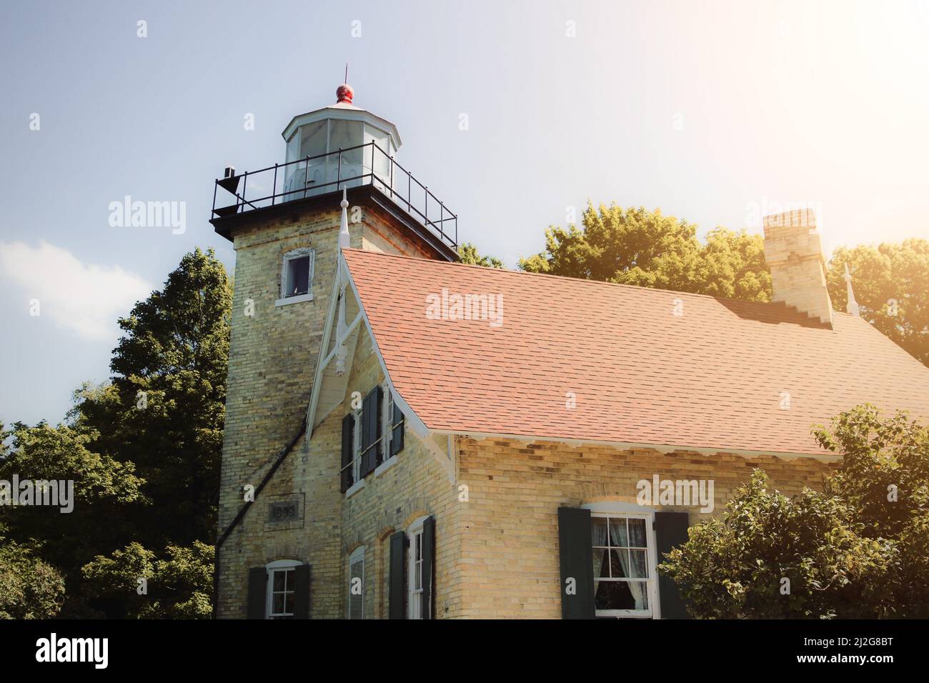 An old lighthouse cottage building surrounded with trees under a bright ...