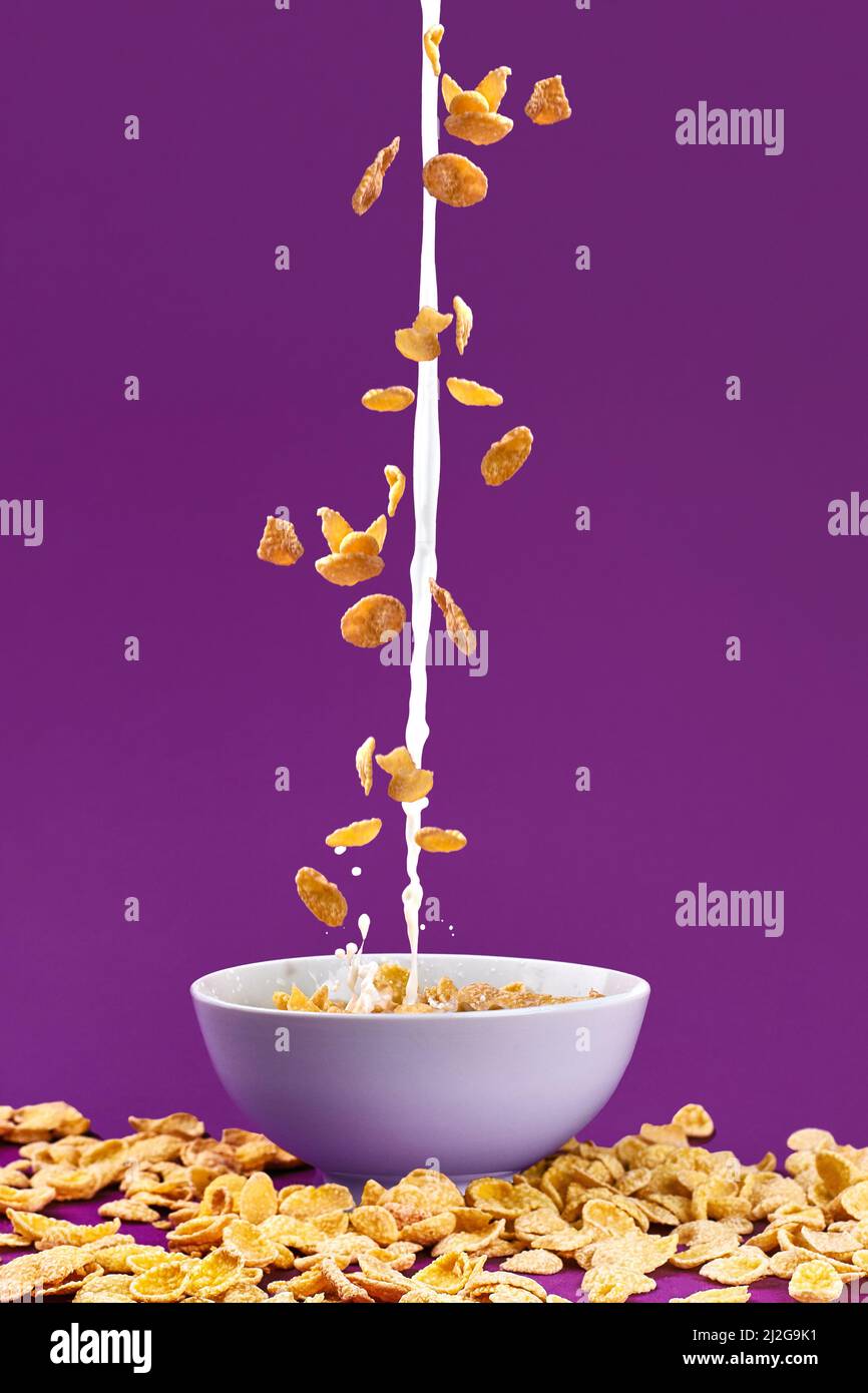 Falling granola with milk splash in bowl. Healthy breakfast ingredients ...