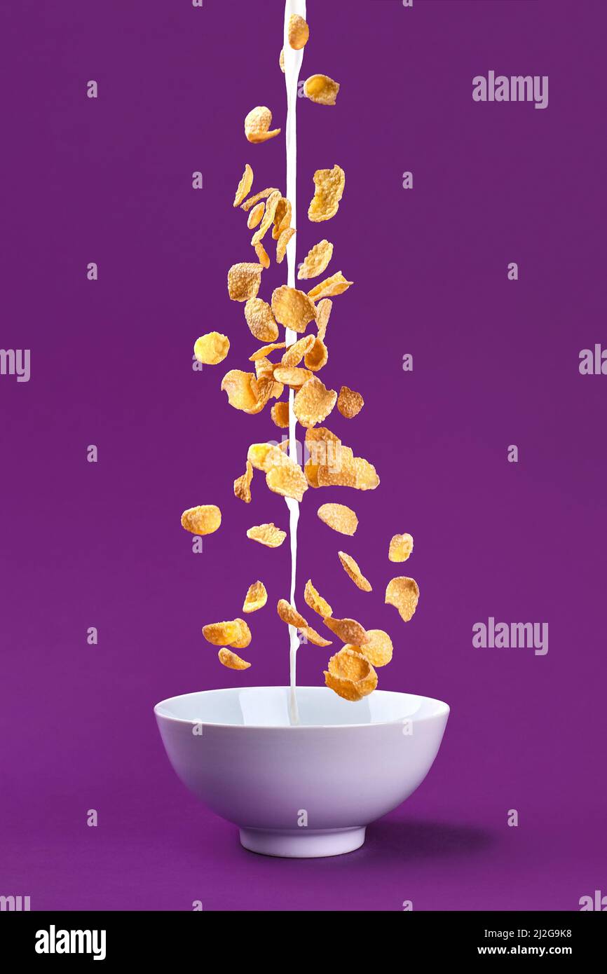 Falling granola with milk splash in bowl. Healthy breakfast ingredients ...