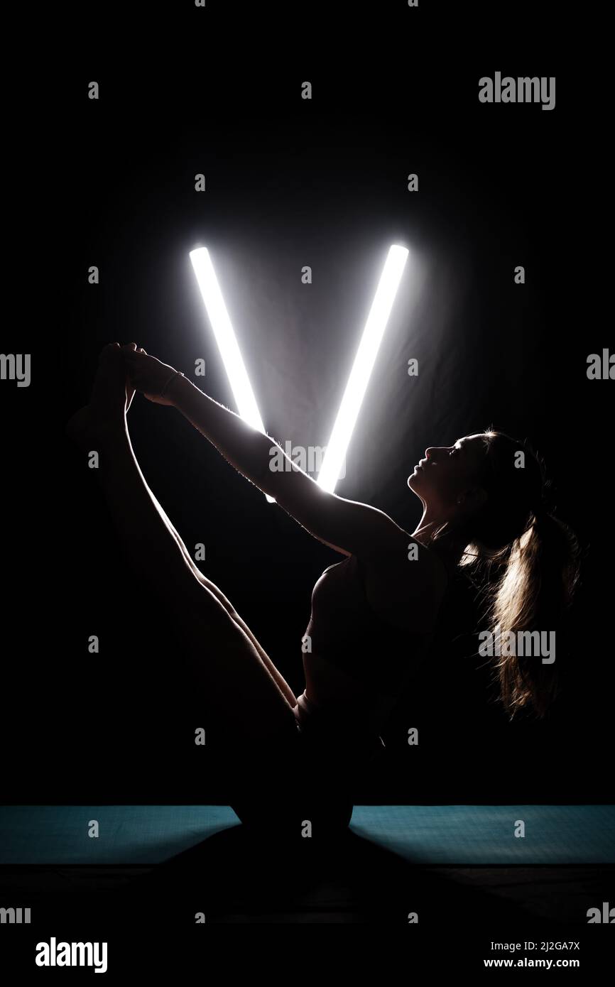 Fit woman practicing yoga poses. Silhouette girl doing exercise in ...