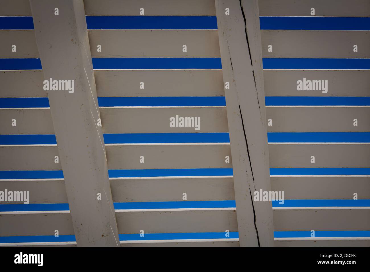 A closeup of white wooden shutters with a bright, clear blue sky ...
