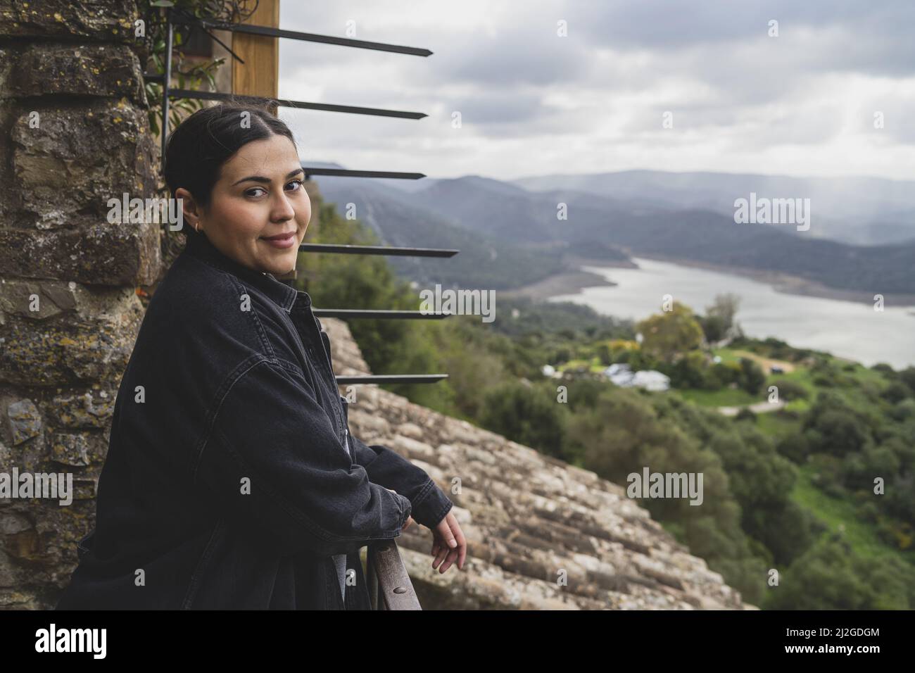 A photo of a Caucasian woman leaning over balcony railing and looking ...