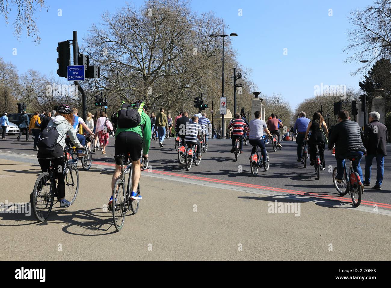 Cyclists crossing the road at Hyde Park Corner in early spring sunshine ...