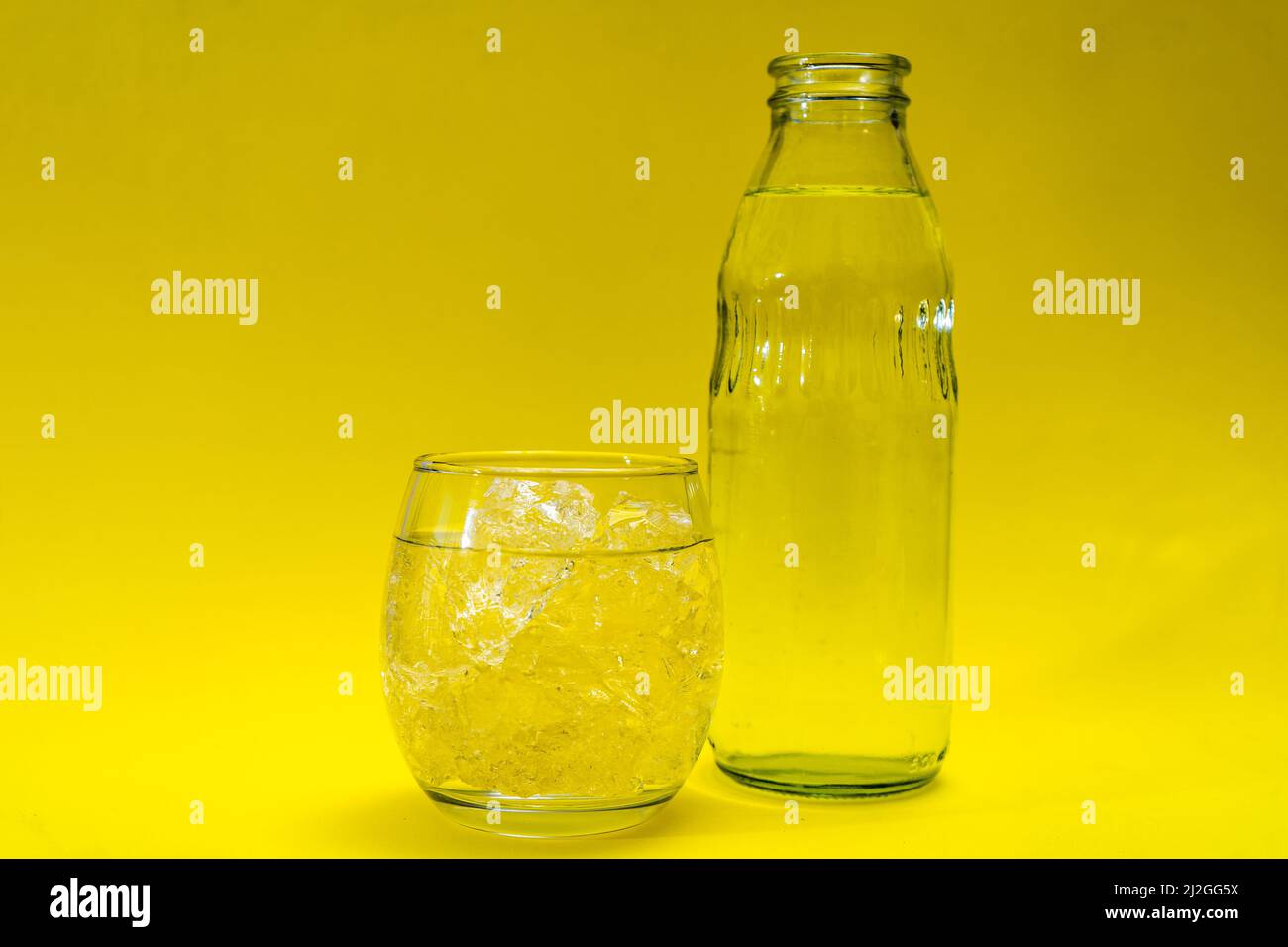 Glass beaker and bottle filled with ice and purified water. Yellow ...