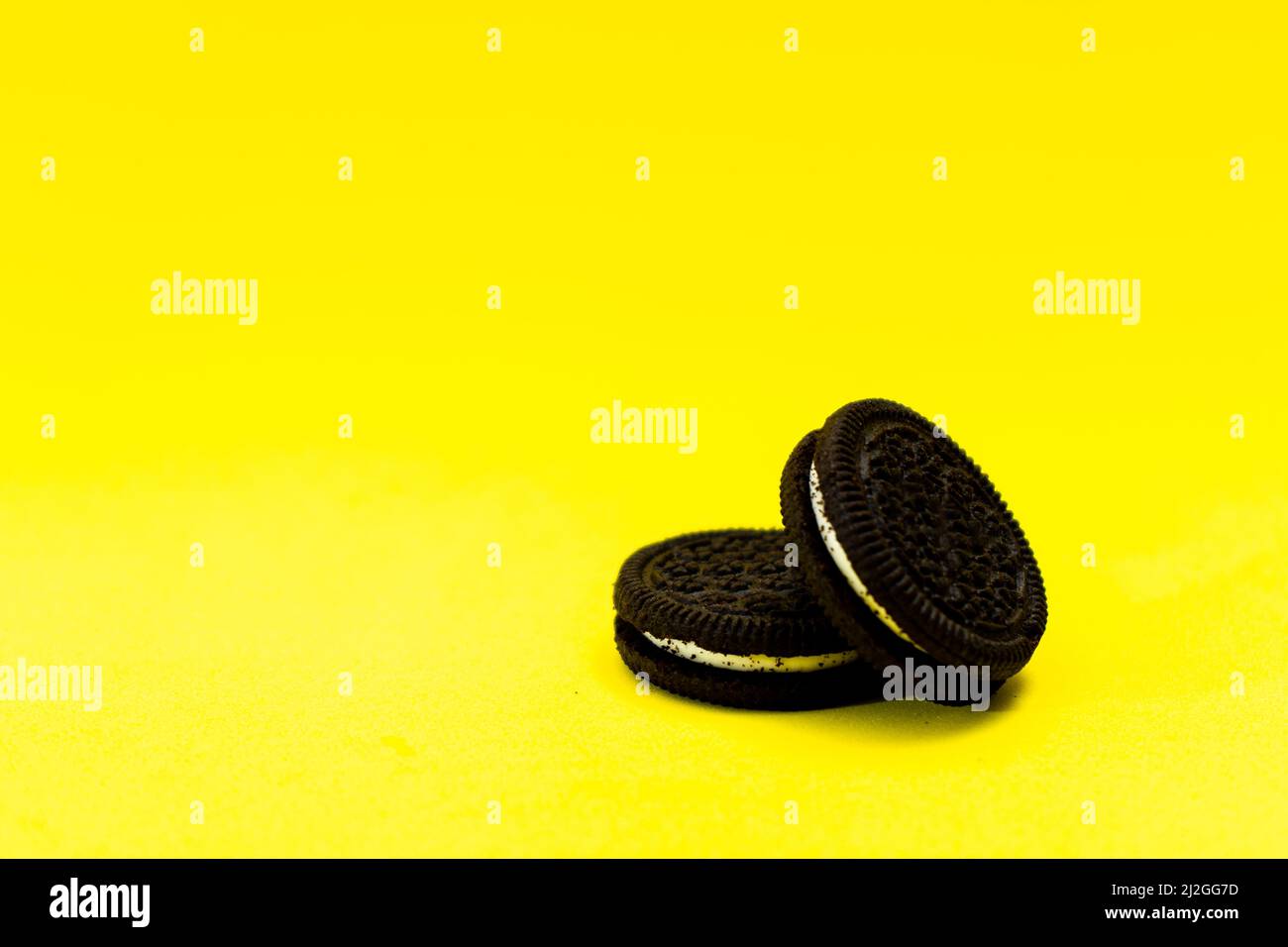 Two chocolate sandwich cookies with sweet cream on a yellow surface ...