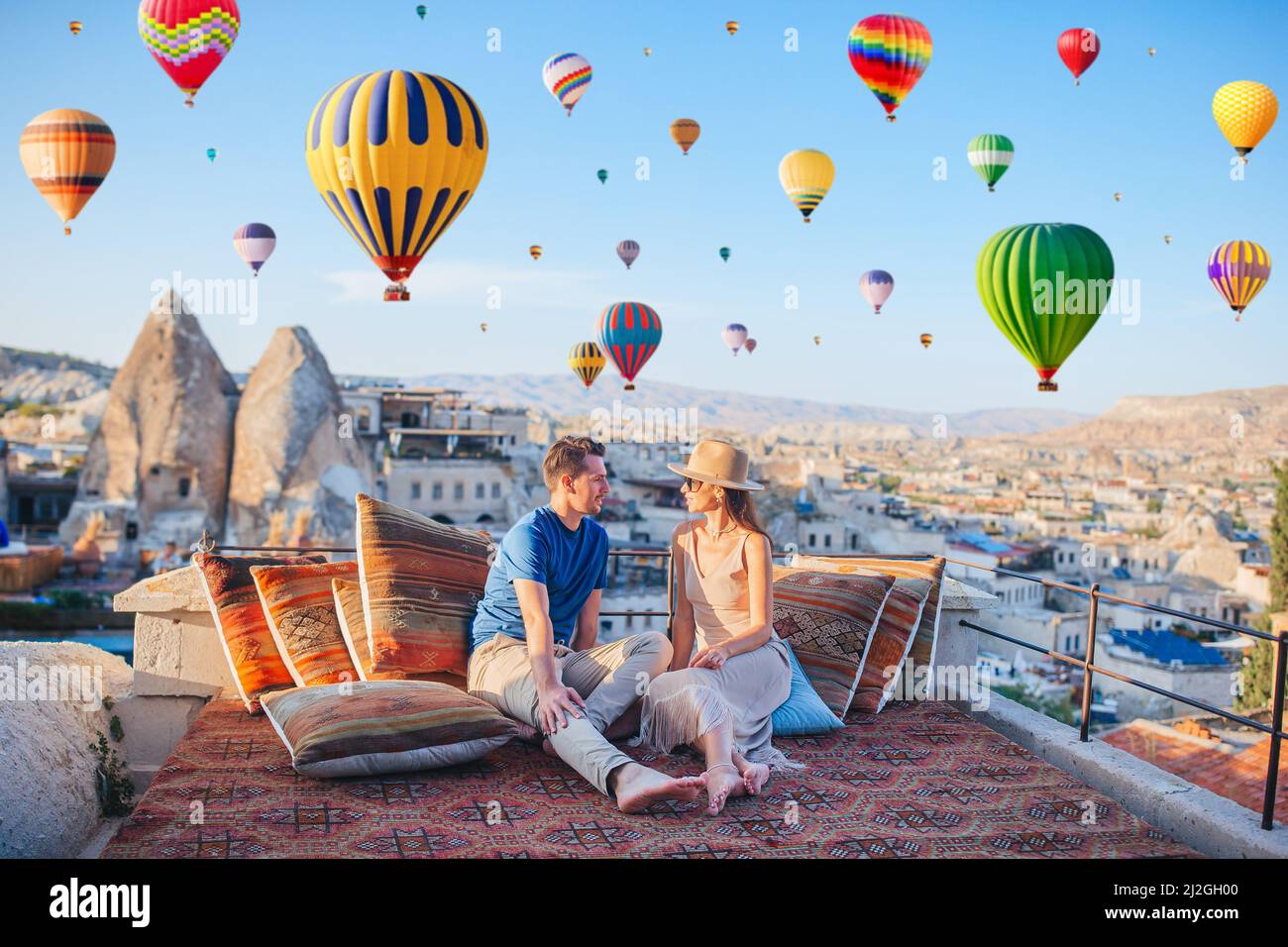 Happy couple in love on a rooftop in Cappadocia with hot air balloons ...