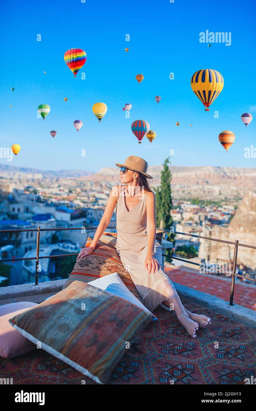 Young woman in Cappadocia. Woman on a rooftop with air balloons in ...
