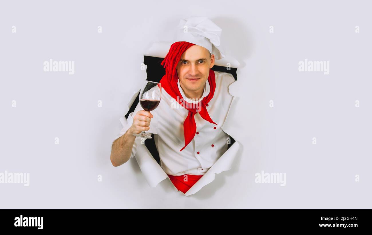 Male cook drinking alcoholic beverage and sticking out of hole of white ...