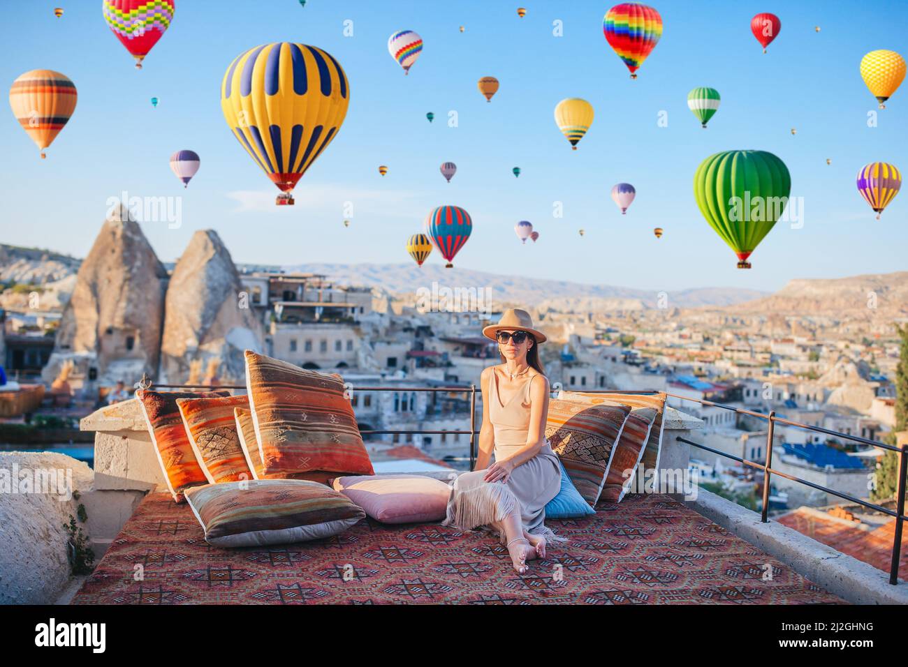 Young woman in Cappadocia. Woman on a rooftop with air balloons in ...