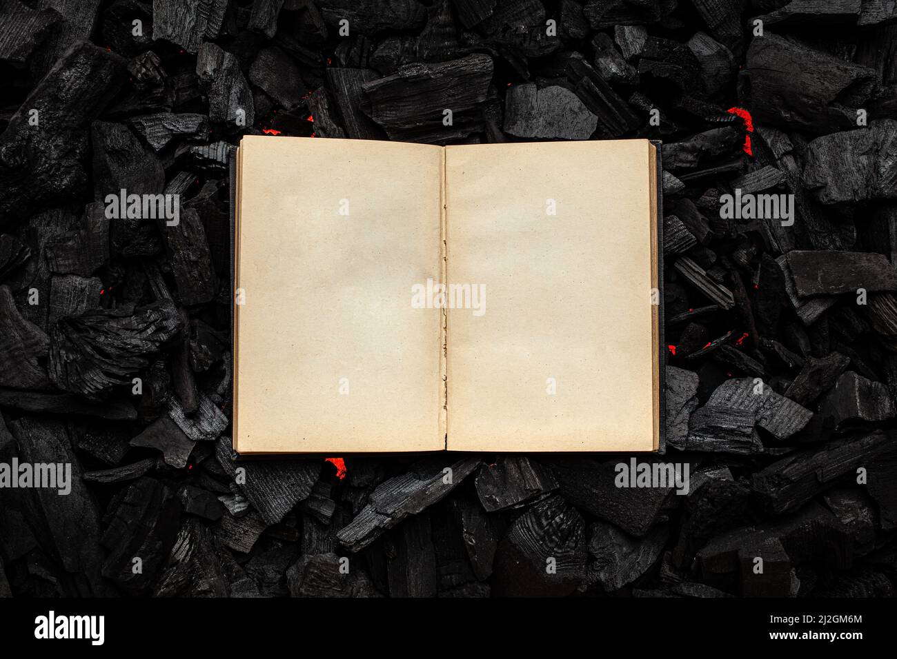 An open book with a black cover on smoldering charcoal. Textured dark ...