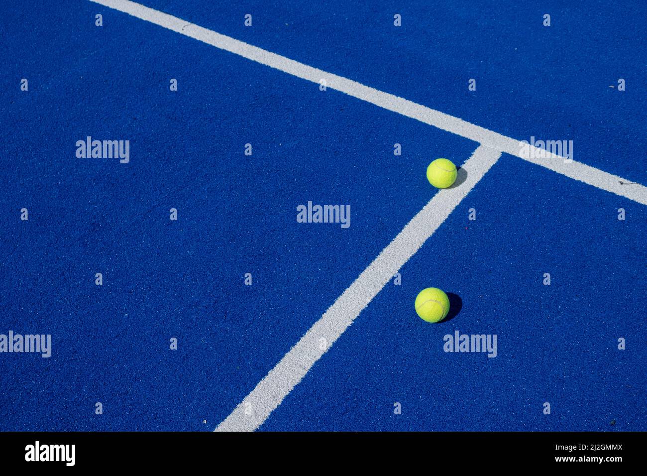 two balls next to the center line on a blue paddle tennis court Stock ...