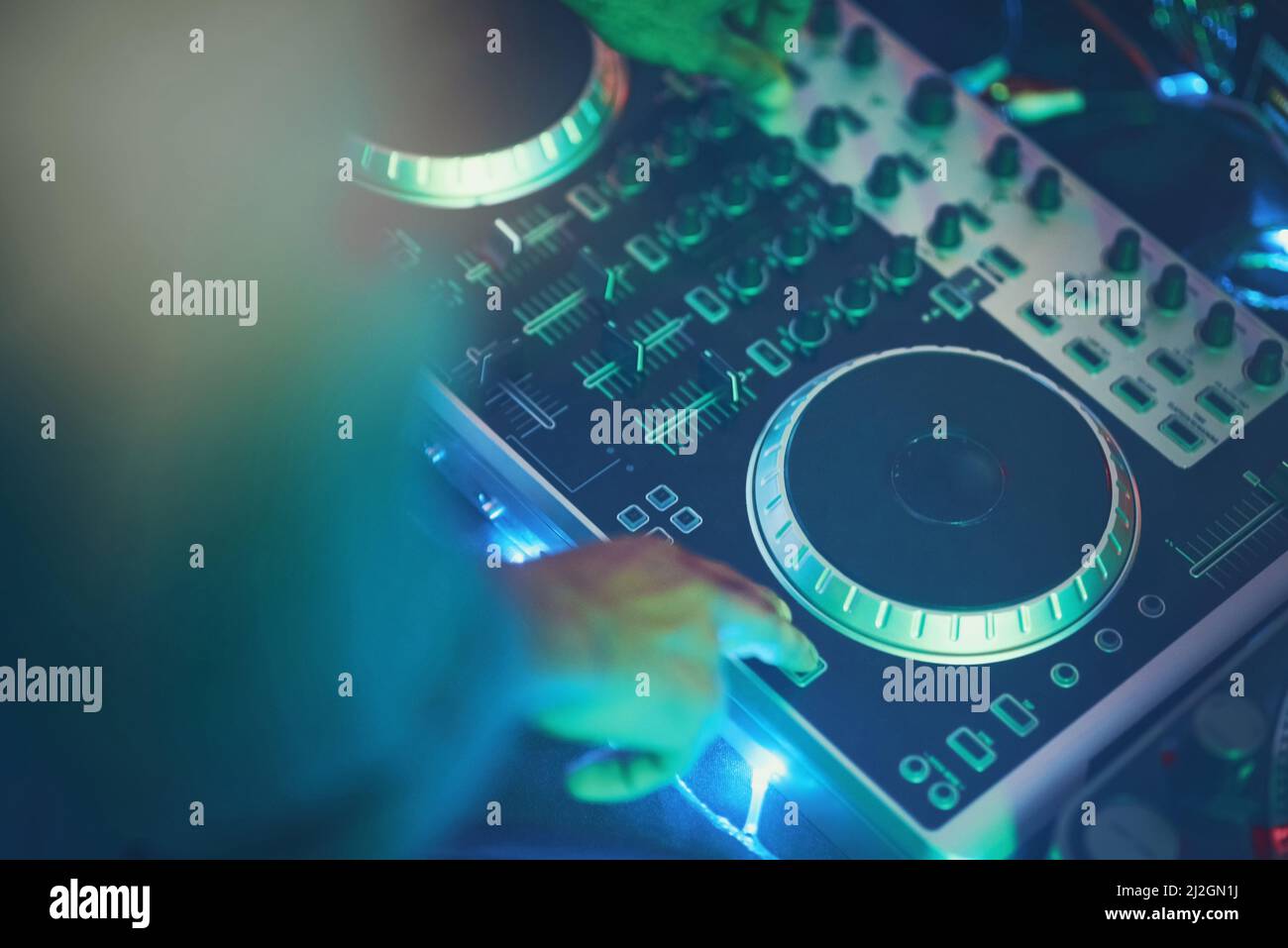 Turning up the volume. Shot of an unidentifiable DJ making music in a ...