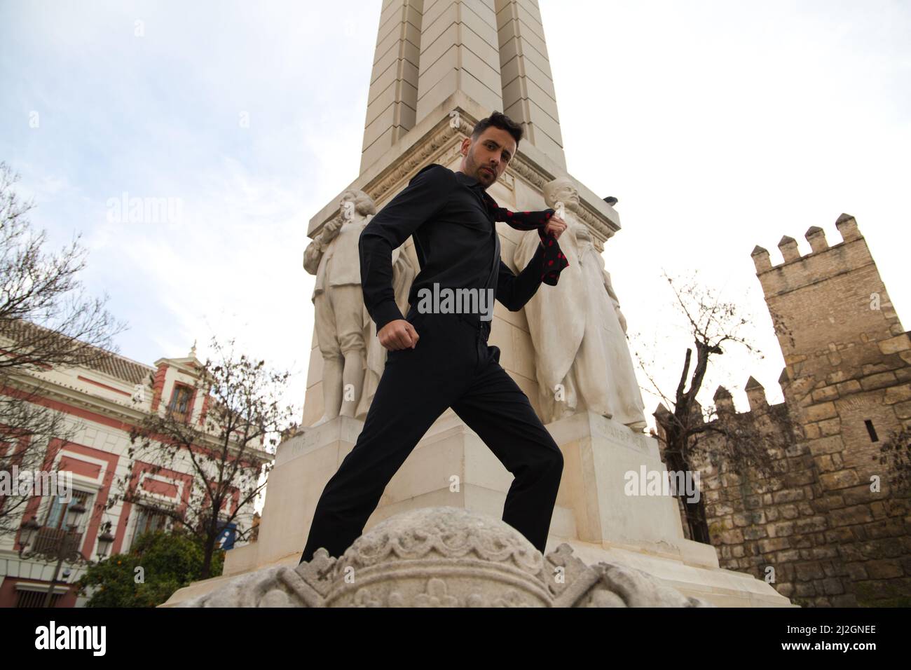 A young and handsome man dancing flamenco on a street, dressed in black ...
