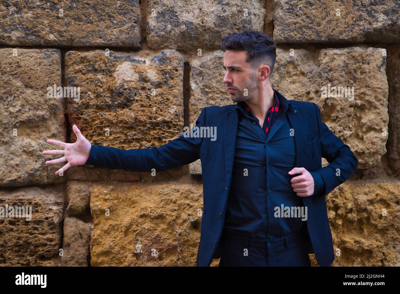 A gypsy man dancing flamenco, wearing black outfit and red shoes, on a ...