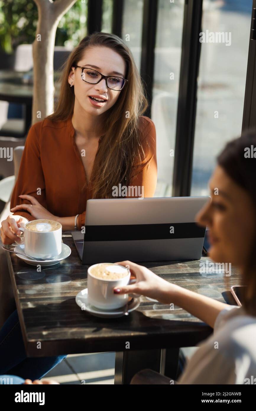Two young business women in a cafe having one on one meeting. Friends ...