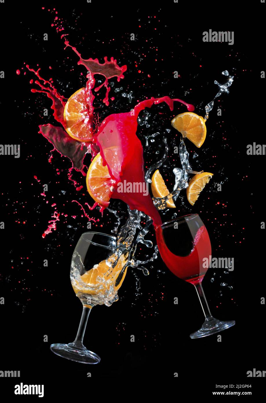 A vertical shot of splashing cocktails in the air in the dark ...