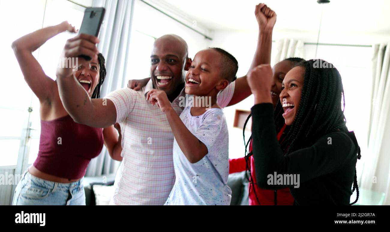 African family celebrating success cheering holding cellphone device ...