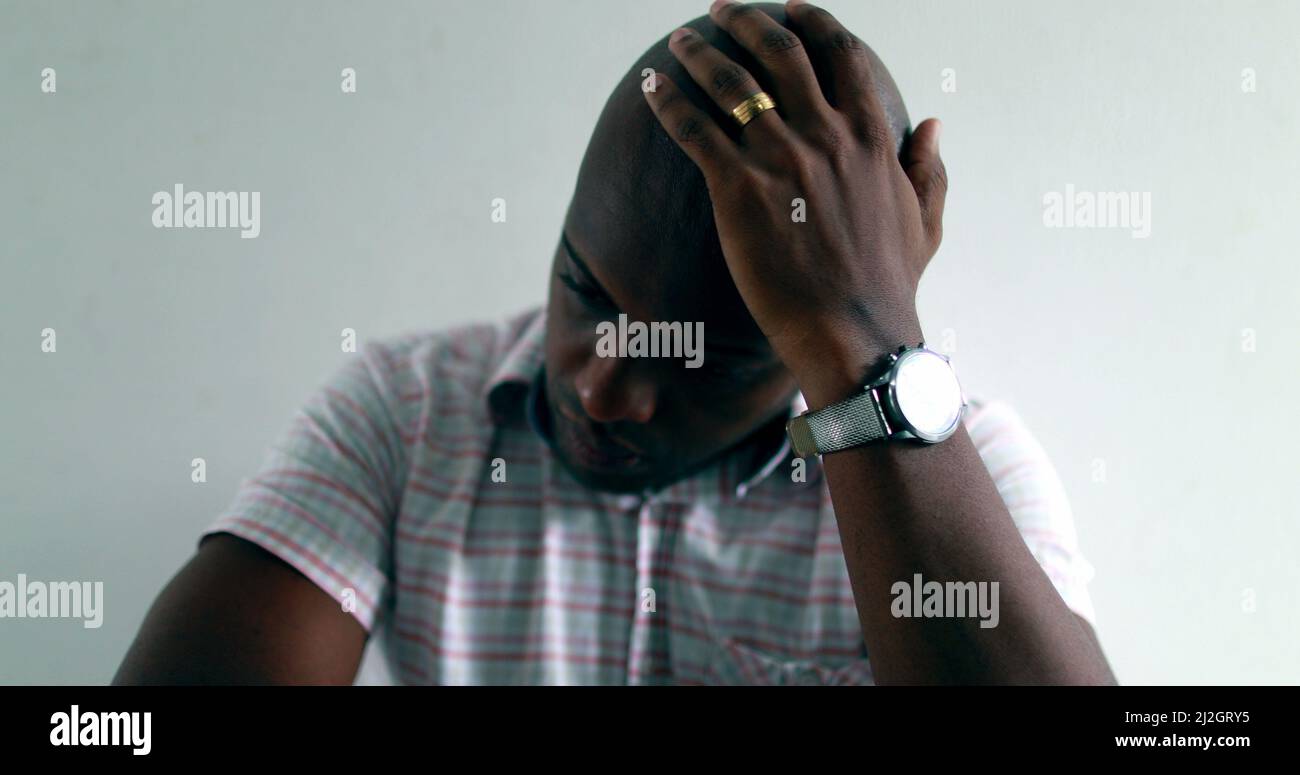 Desperate black African man sitting on home floor in despair and ...