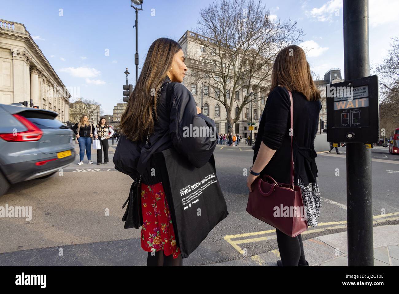 Pedestrians London; two women waiting at a pedestrian crossing to cross ...