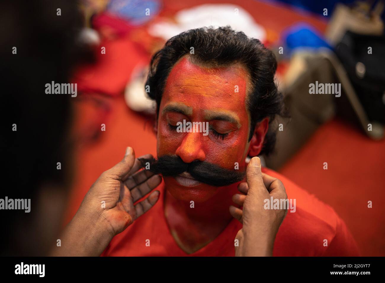 Face makeover artist attaching fake moustache to face of man supposed ...