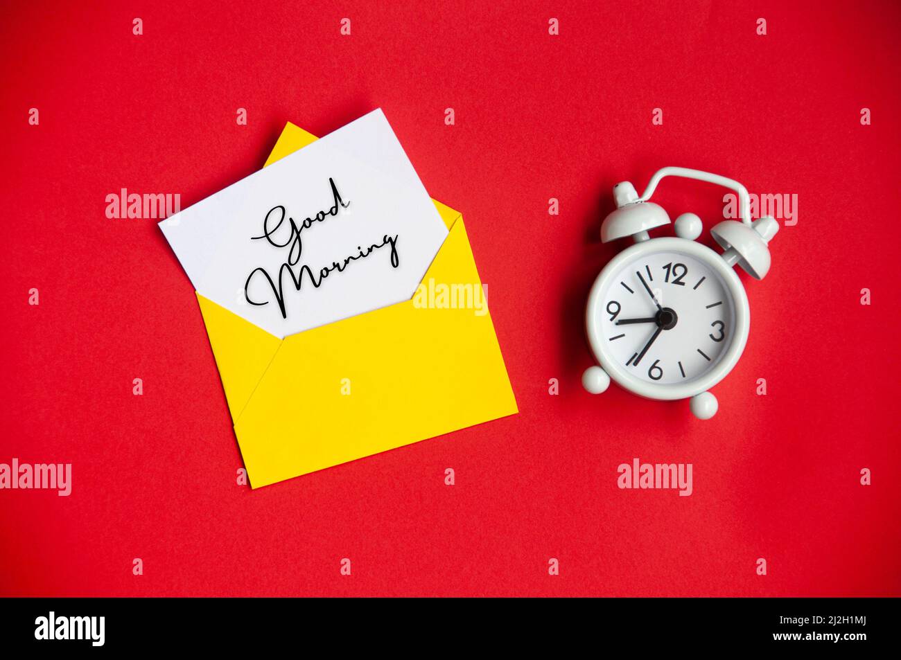 Good morning text on white notepad with envelope and alarm clock ...
