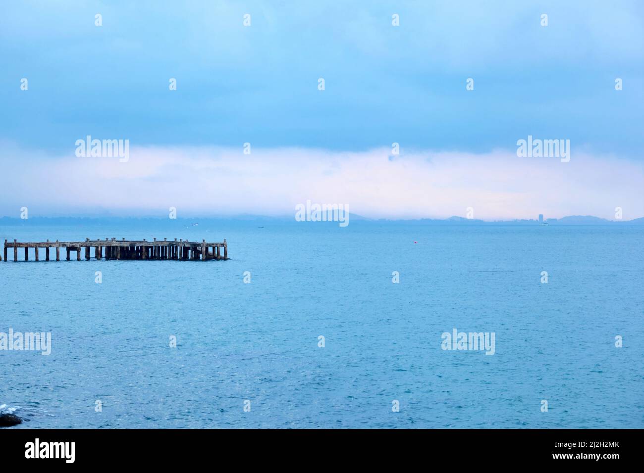 Thick clouds across the blue sea with pier Stock Photo - Alamy