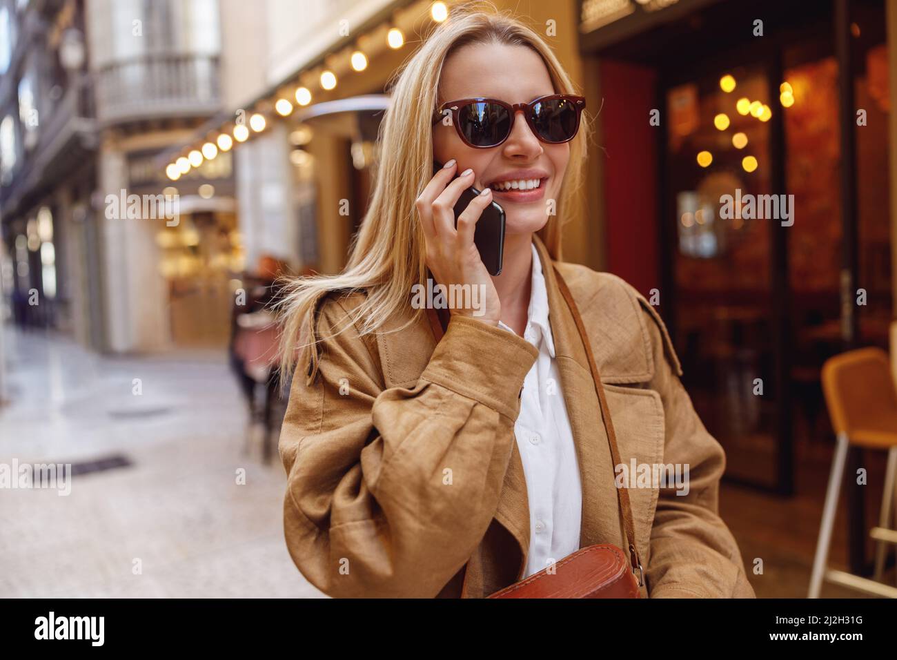 Portrait of lady in sunglasses calling by phone while standing on ...