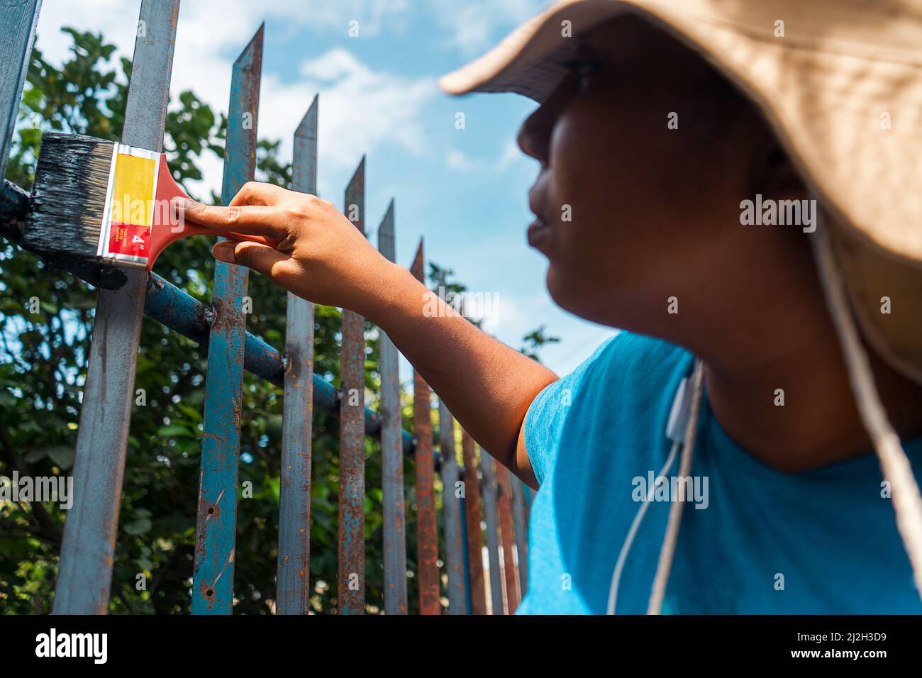Latin young woman waring a sun hat painting a fence Stock Photo - Alamy