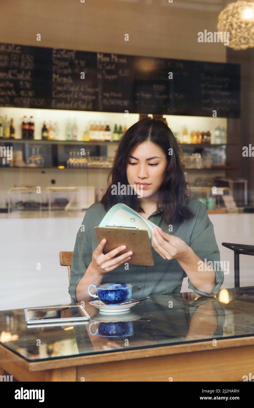Woman looking at menu in cafe Stock Photo - Alamy