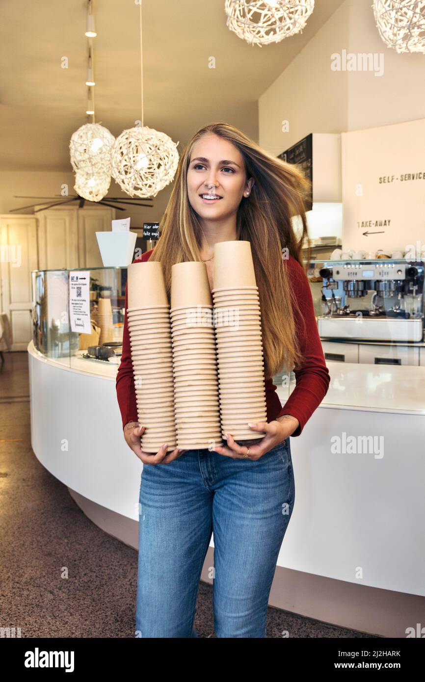 Portrait of woman carrying stacks of disposable cups in cafe Stock ...