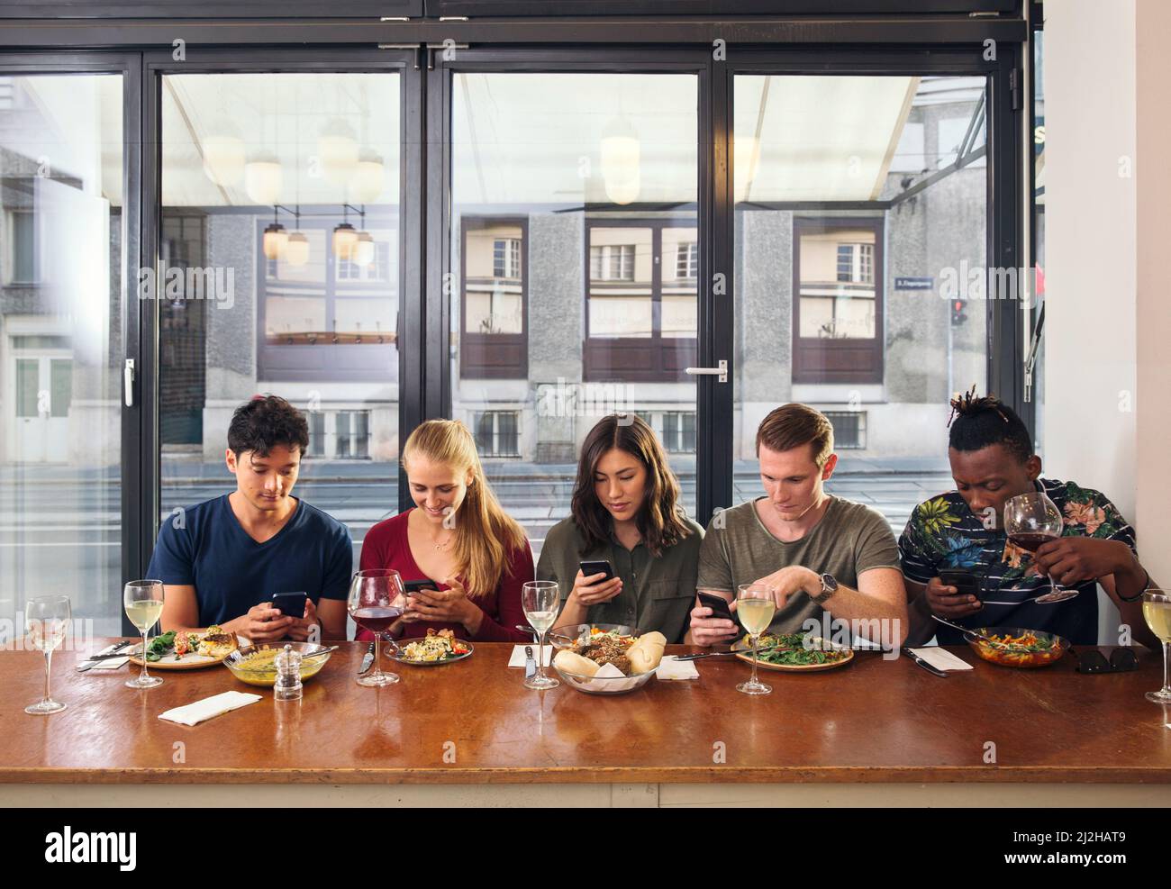 Friends having meal and looking at smart phones in restaurant Stock ...