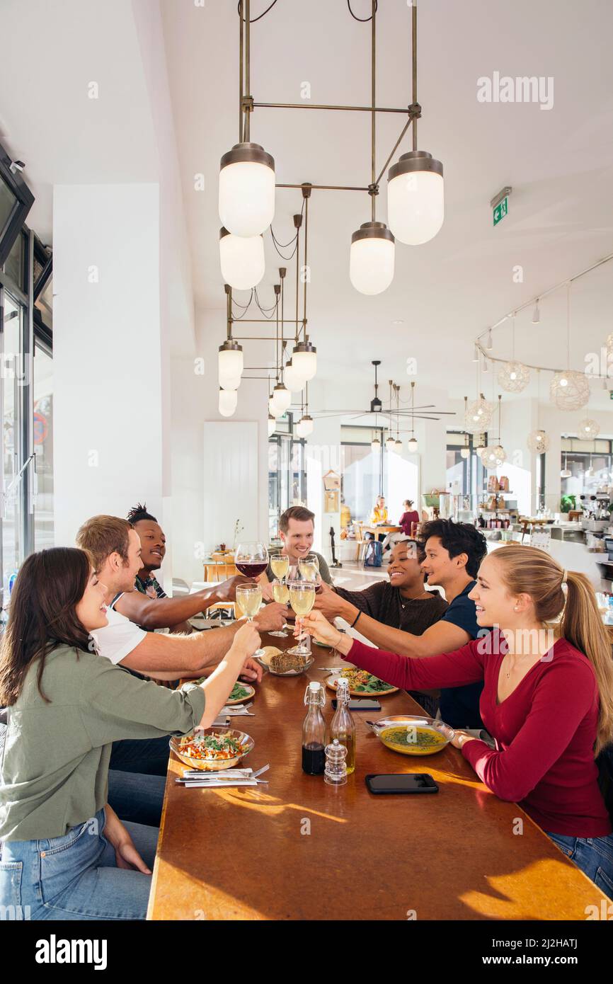 Group of friends toasting with white wine in restaurant Stock Photo - Alamy