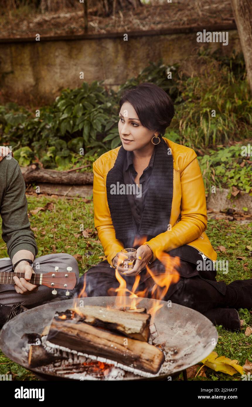 Friends having picnic around fire pit in garden Stock Photo - Alamy