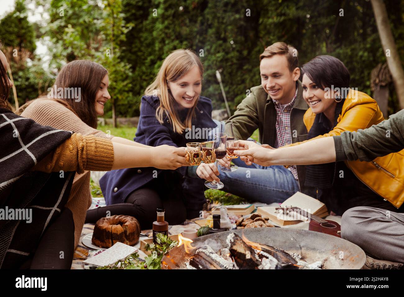 Group of friends toasting around fire pit in garden Stock Photo - Alamy
