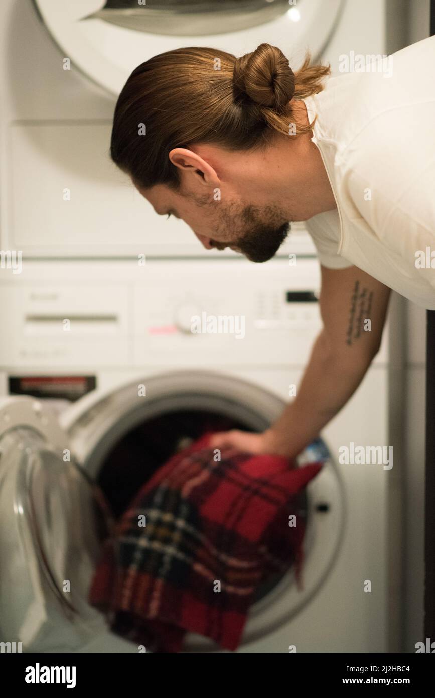 Man putting clothes into washing machine Stock Photo - Alamy